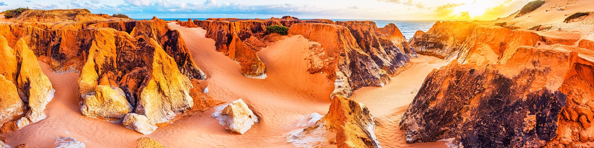 Paisagem acidentada com formações rochosas erodidas e um rio serpenteando por um cânion.