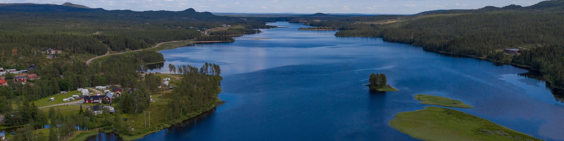 Um rio serpenteia por uma paisagem arborizada com casas às margens.