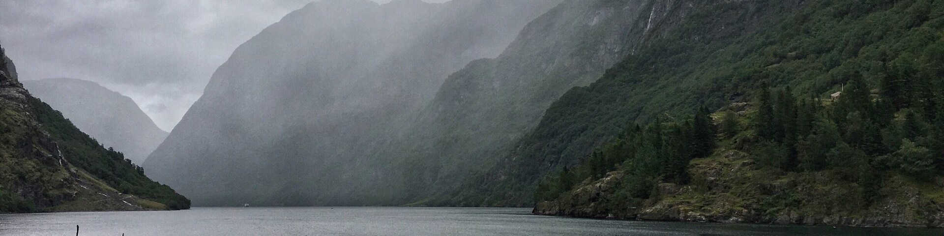 Um rio serpenteando por uma paisagem montanhosa com margens rochosas e um barco em primeiro plano.