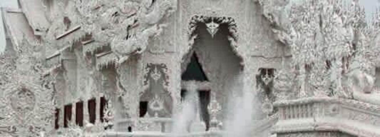 Um templo branco e ornamentado, com uma fonte central e uma ponte.