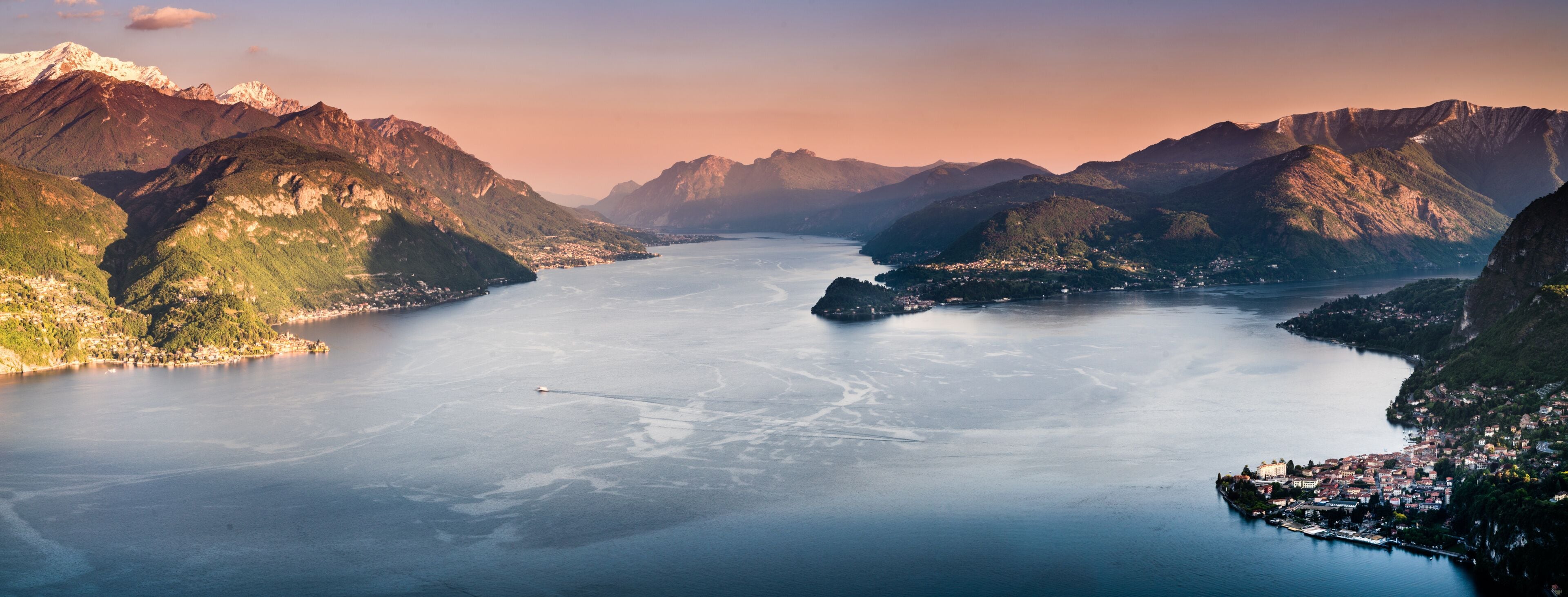 Paisagem montanhosa com um rio, uma cidade pequena e um barco.