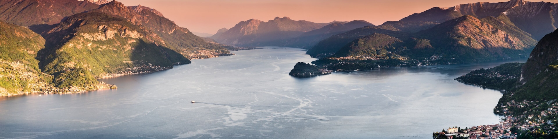 Paisagem montanhosa com um rio, uma cidade pequena e um barco.