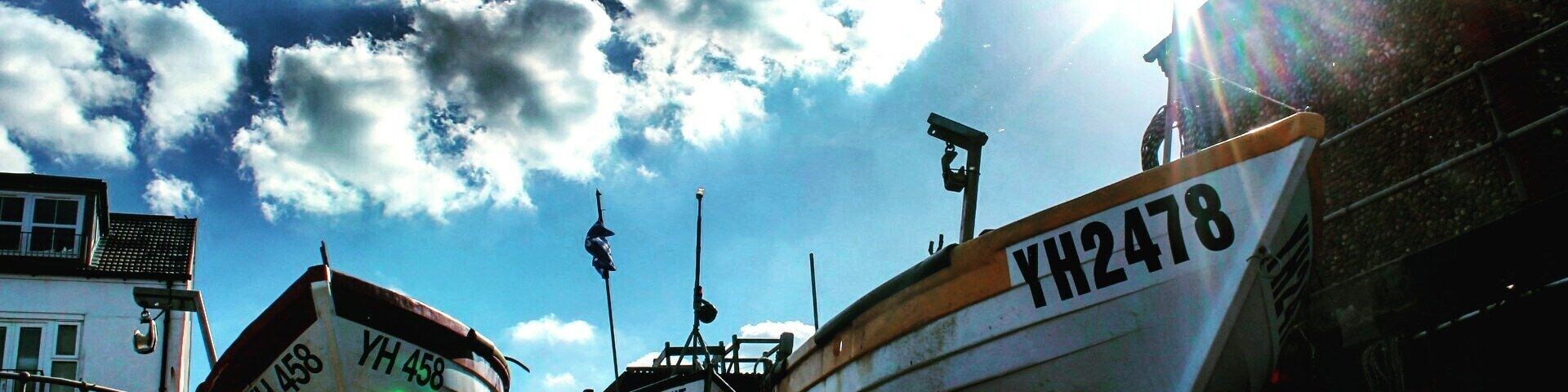 Três barcos atracados num cais sob um céu limpo e luz solar.