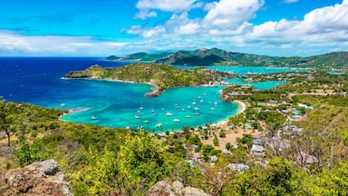 Paisagem costeira com águas azul-turquesa, barcos e montanhas ao fundo.