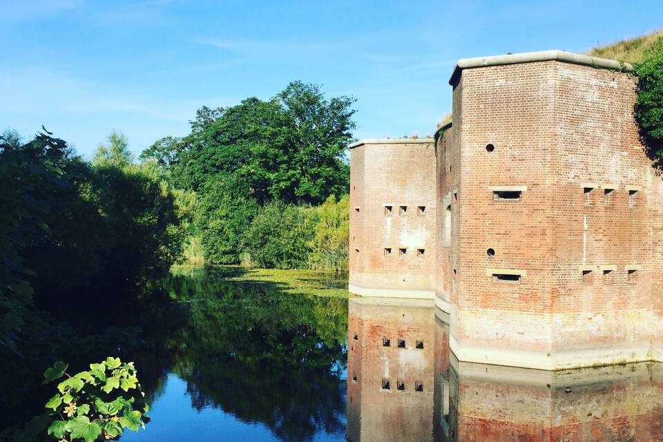 Um castelo de tijolos com fosso e vegetação exuberante.