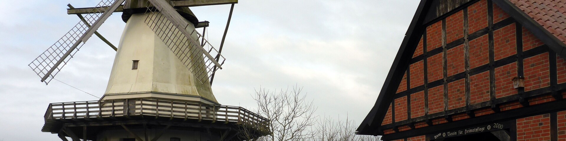 Die Windmühle (links) und das benachbarte Fachwerkgebäude (rechts) in Tonnenheide (Ortschaft der Stadt Rahden) aus östlicher Richtung.