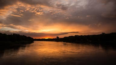 Pôr do sol sobre um rio, com céu nublado.