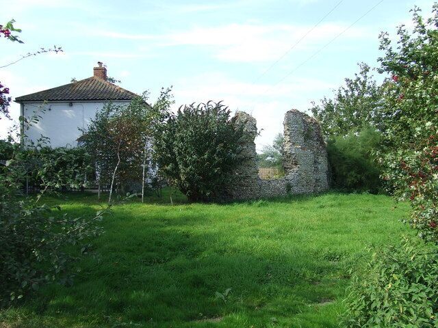 Uma casa branca, ruínas de pedra e vegetação exuberante.