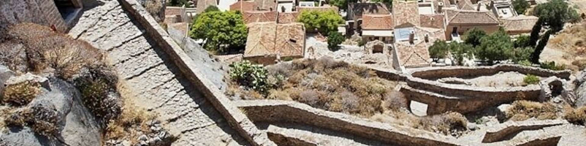 Estrutura antiga de pedra com vista para uma vila costeira.