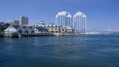 Um calçadão com um pier, um edifício histórico e arranha-céus modernos.