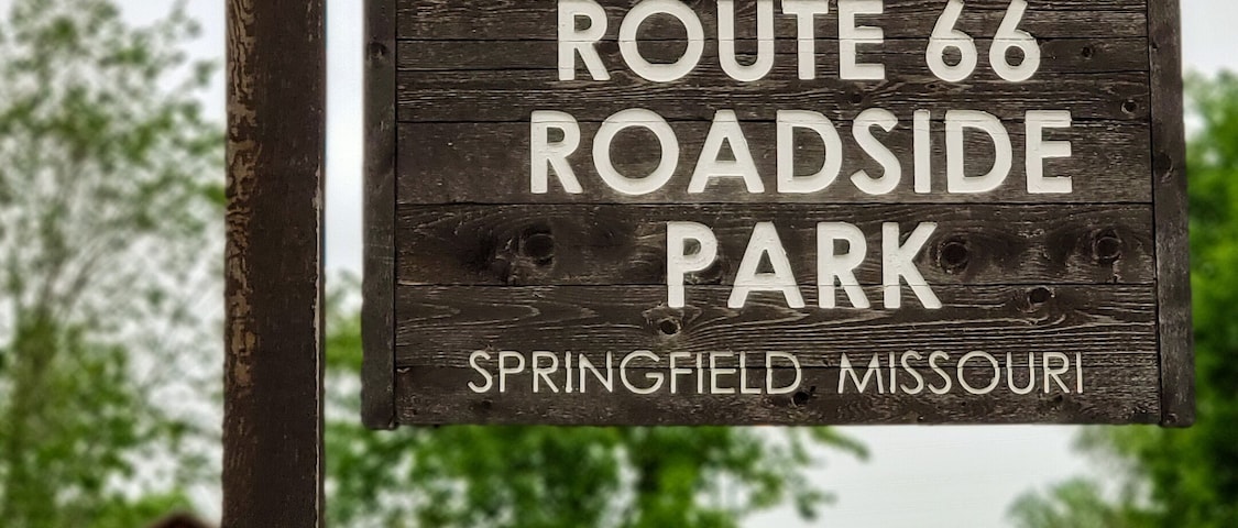 Placa de madeira com a inscrição 'Birthplace of Route 66 Roadside Park' em Springfield, Missouri.