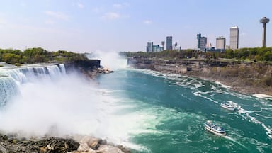 Uma cachoeira imponente, um rio, o horizonte urbano de uma cidade e uma torre.
