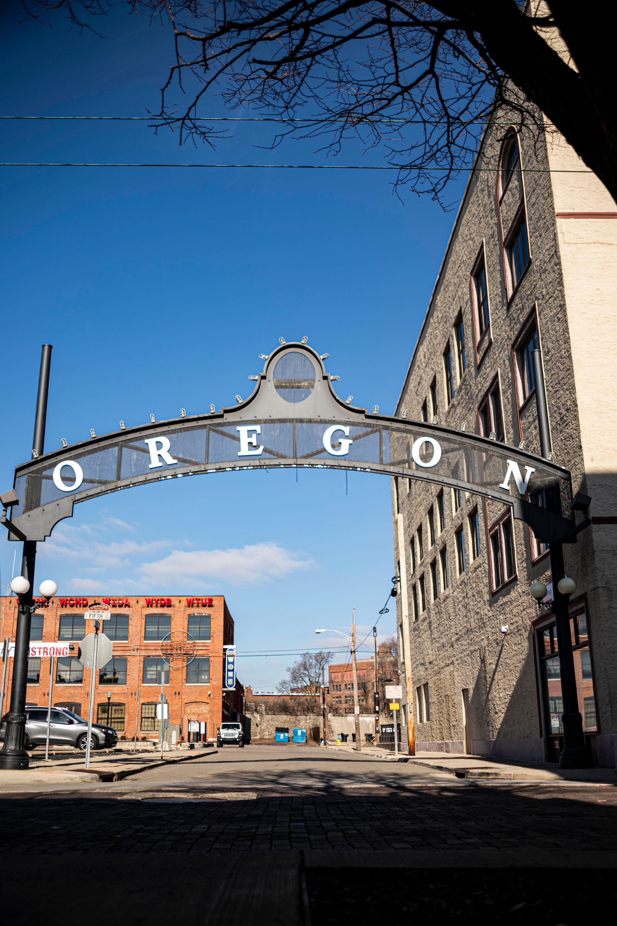 Uma placa de rua com a palavra 'OREGON', um edifício de tijolos e um céu azul claro.