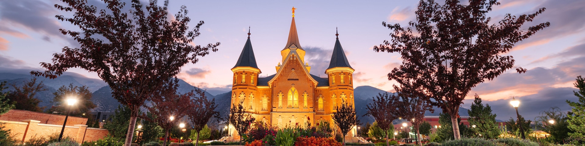 Uma igreja com duas torres, rodeada por jardins bem cuidados e árvores.