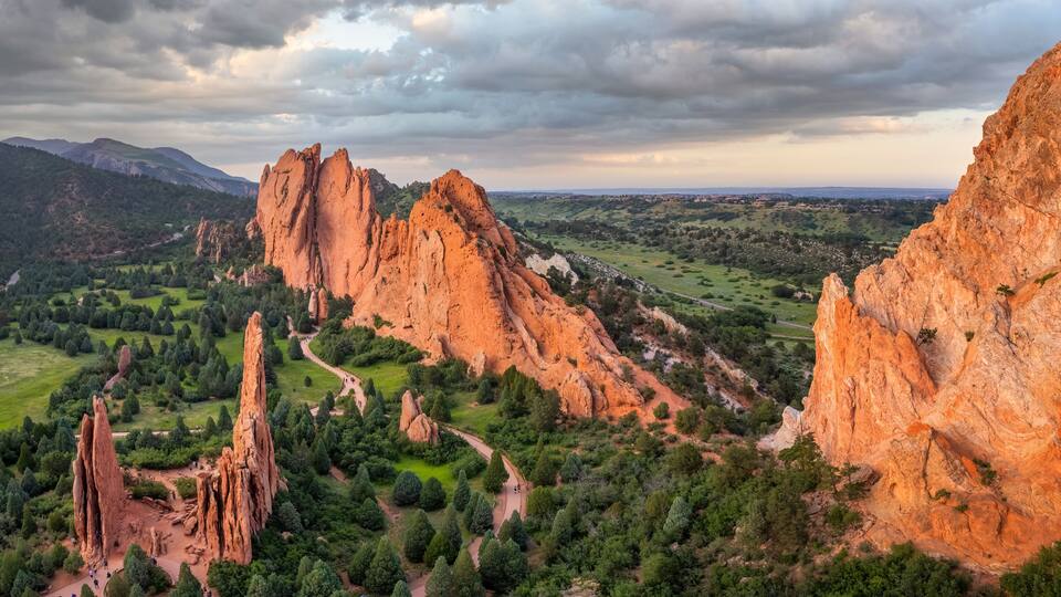 Paisagem montanhosa com formações rochosas avermelhadas e um caminho sinuoso.