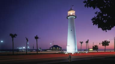 Um farol alto e branco ao entardecer, sob um céu roxo.