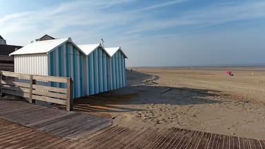 Uma passarela de madeira que leva a cabanas de praia com toldos listrados.