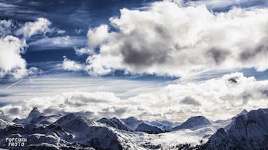 Uma cordilheira coberta de neve com céu parcialmente nublado.