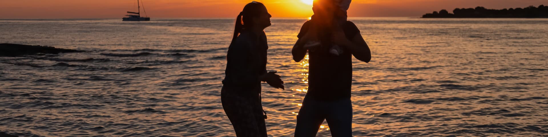 Um pôr do sol sobre o oceano, com um veleiro ao longe.