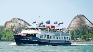 Um barco chamado 'GOODTIME I' com várias bandeiras, incluindo a bandeira americana, navegando em águas com montanhas-russas ao fundo.