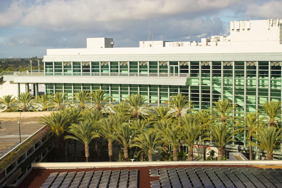Um edifício moderno com fachada de vidro e painéis solares no telhado.