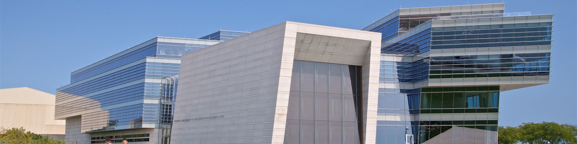 Um edifício de arquitetura moderna com superfícies de vidro refletivas e base de concreto.