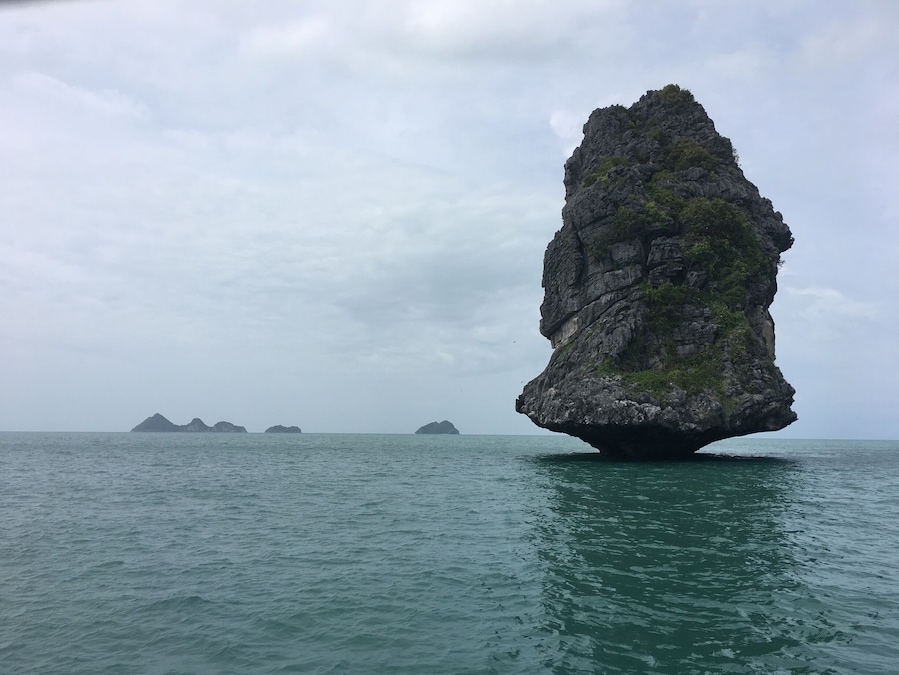 Uma grande formação rochosa no oceano, com ilhas menores ao fundo.