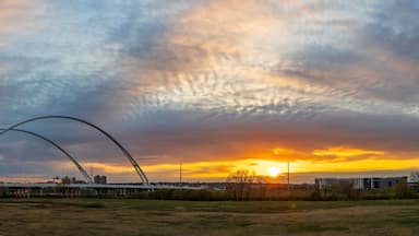 Uma grande ponte em arco sobre um rio, com o pôr do sol ao fundo.