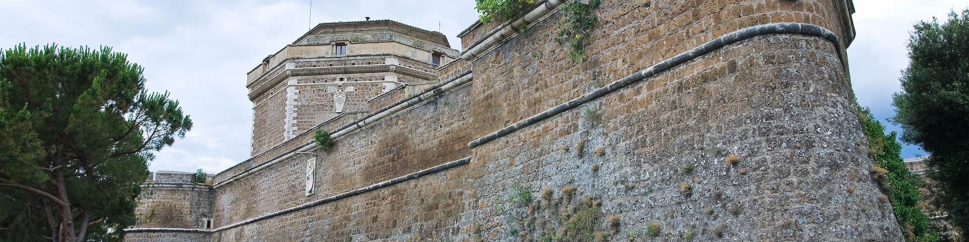 Uma fortaleza histórica de pedra, com ameias e uma torre central.