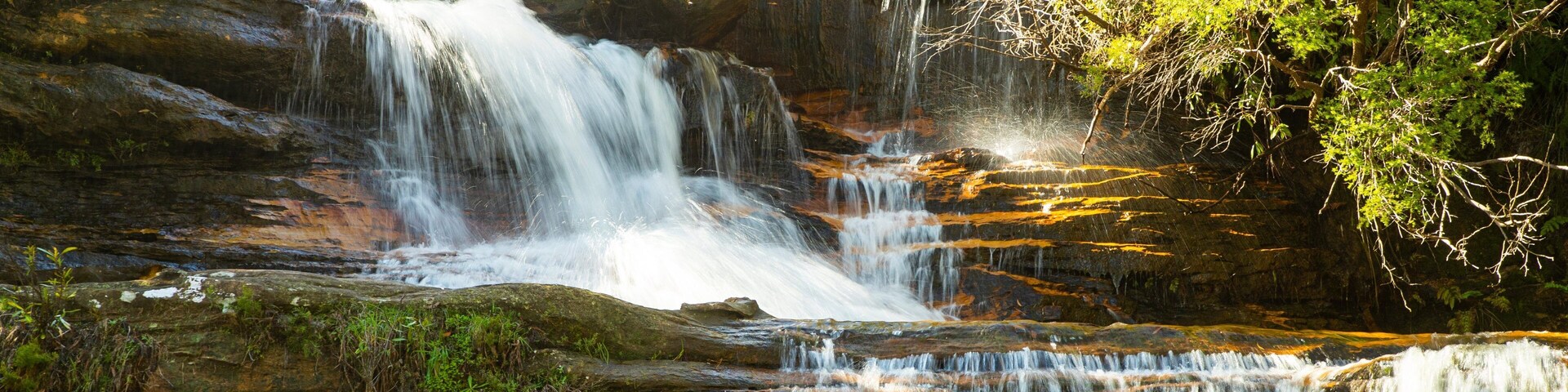 Uma cascata em vários níveis, rodeada por vegetação exuberante.