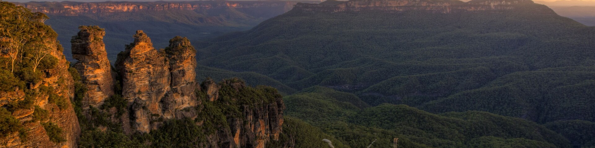 Paisagem montanhosa com formações rochosas imponentes e floresta densa.