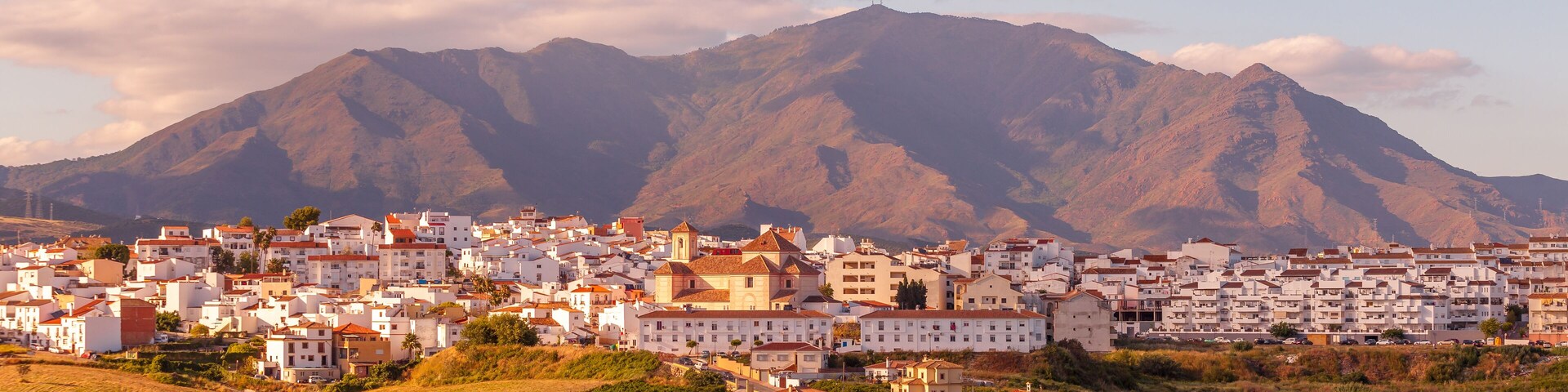 Uma cidade aninhada em um vale, com uma cordilheira ao fundo.
