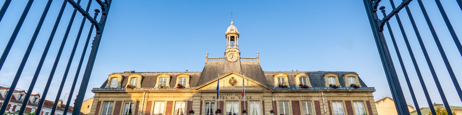 A historic building with a clock tower, ornate iron gates, and a sign reading "Hôtel de Ville."
