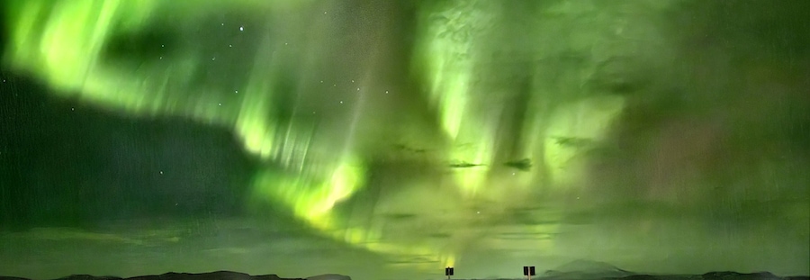 A aurora boreal sobre uma paisagem montanhosa.