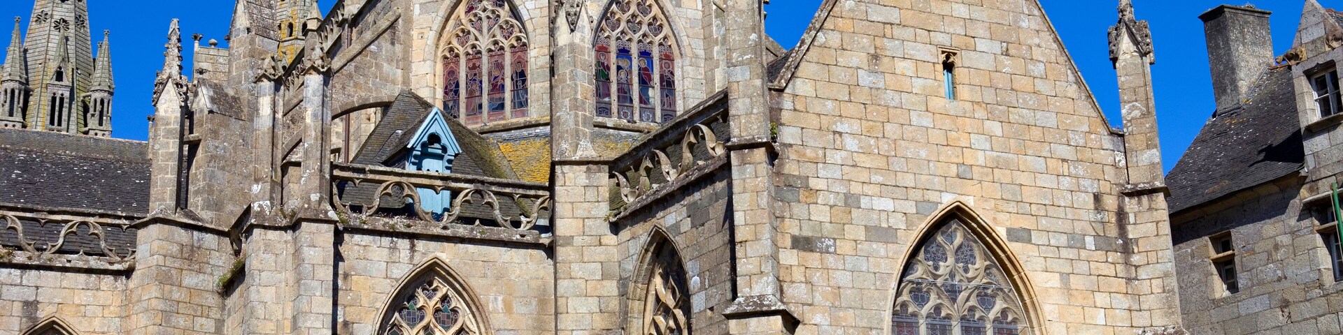 Uma catedral histórica com arcos ogivais, vitrais e uma torre imponente.