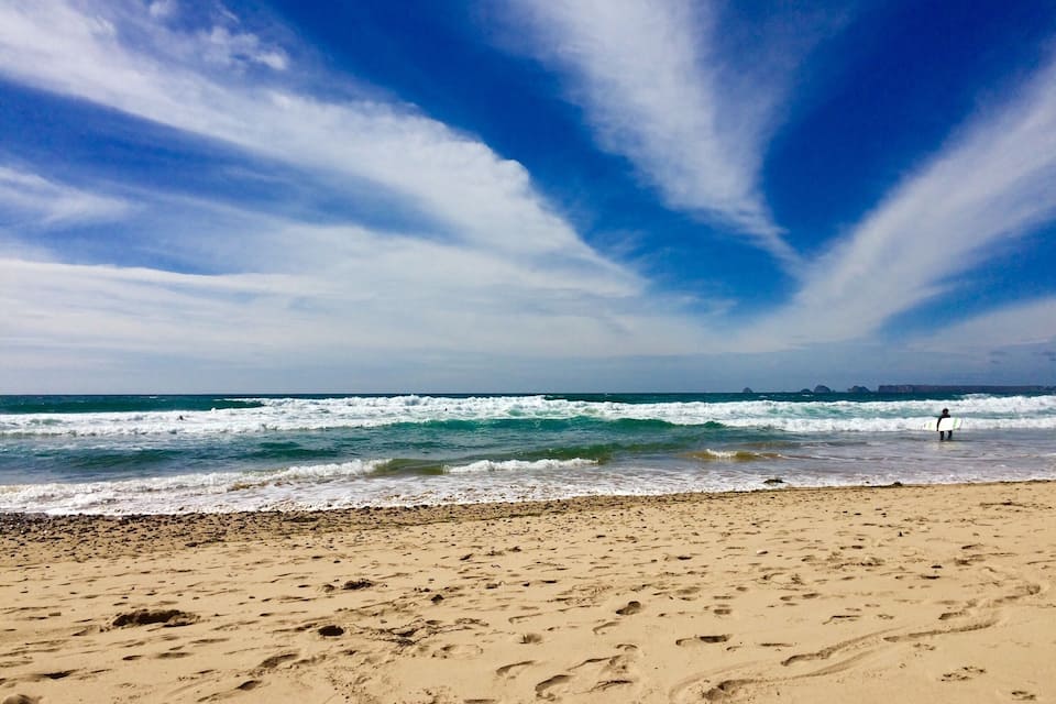 Uma praia com pegadas na areia e ondas quebrando na costa.