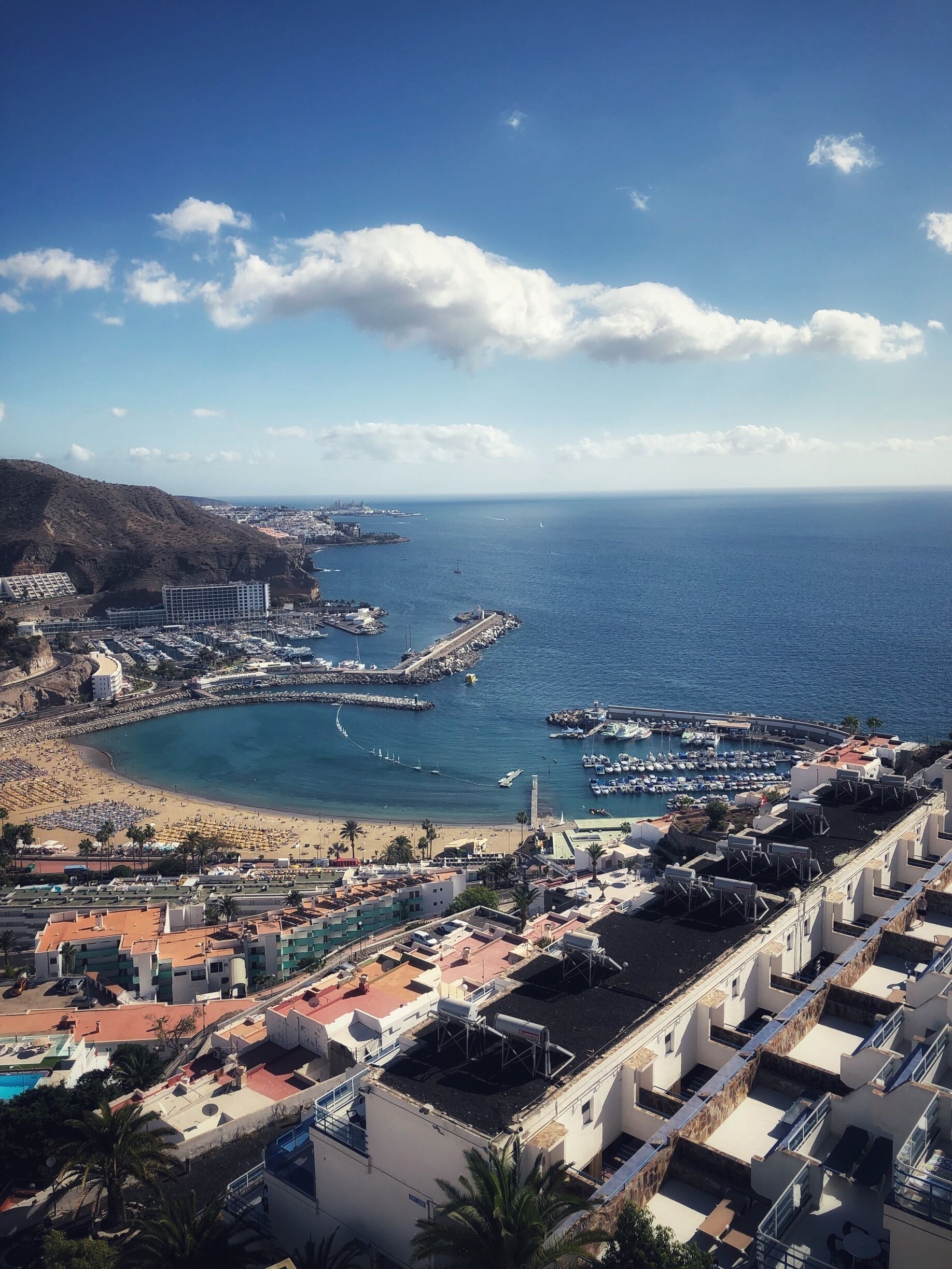 Uma vila costeira com praia, marina e edifícios.