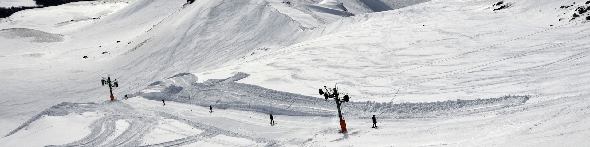 Montanha coberta de neve com pistas de esqui e torres de teleférico.