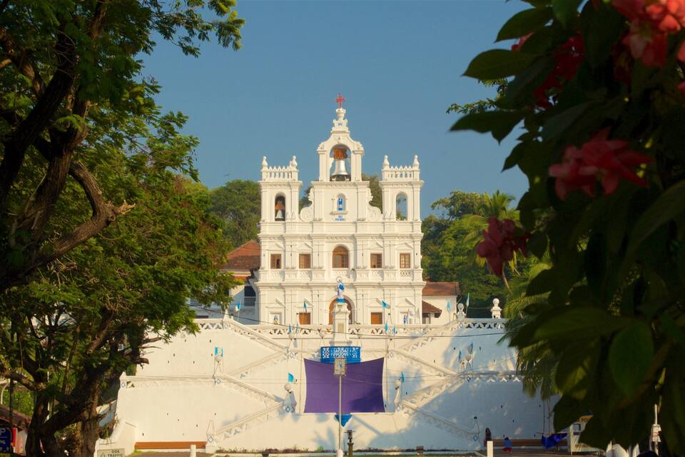 Uma igreja de estilo colonial branco, com um campanário e uma estátua de um santo.