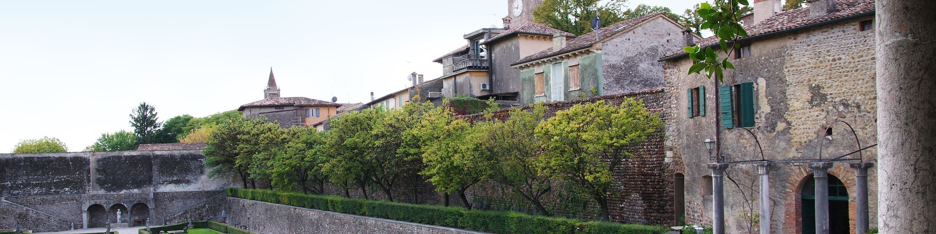 Um pátio histórico com paredes de pedra, jardins bem cuidados e edifícios tradicionais.