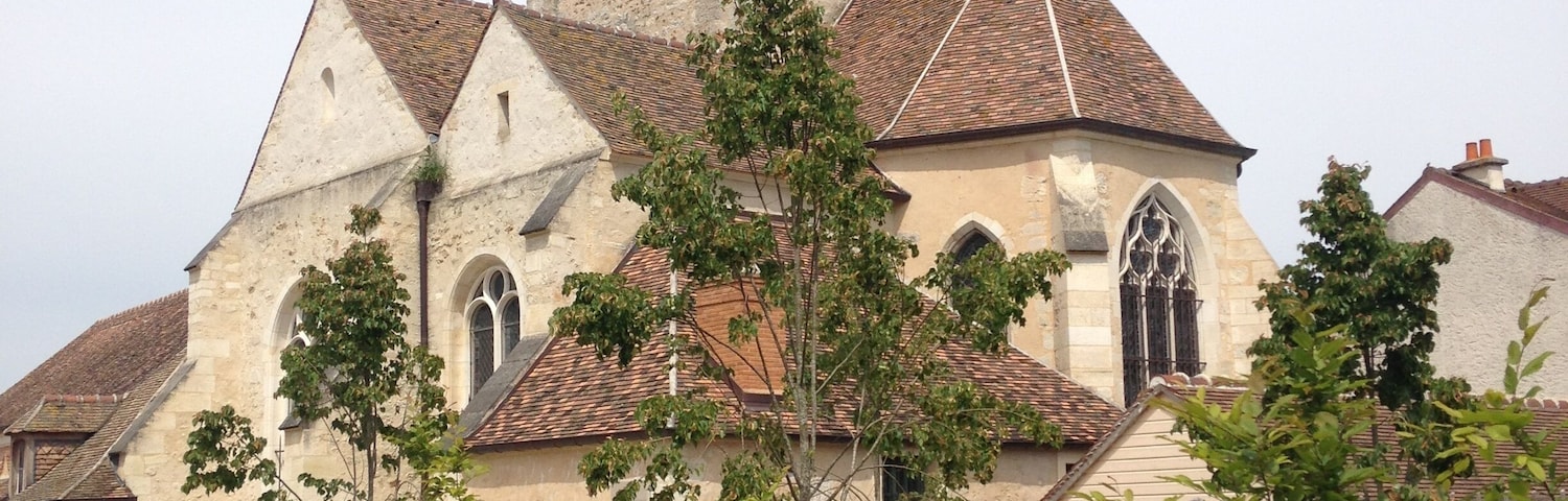 Uma igreja histórica com uma torre alta, janelas em arco e um girassol.