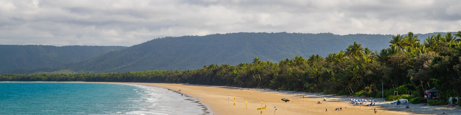 Uma praia com águas turquesa cristalinas, areal arenoso e palmeiras.