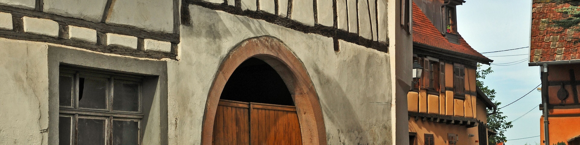 Um edifício de estrutura de madeira e colagem com porta de madeira e janela em arco.