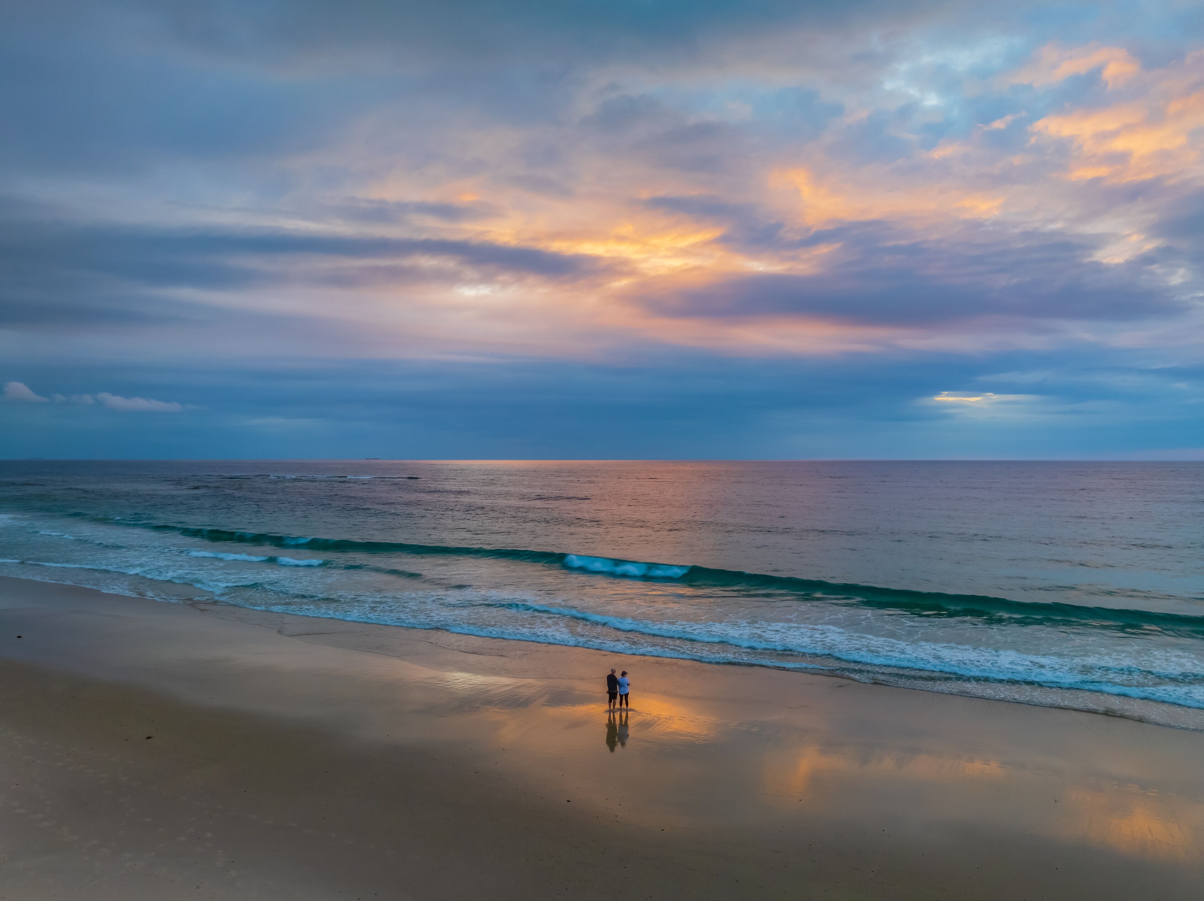Uma praia com ondas e um céu ao pôr do sol.