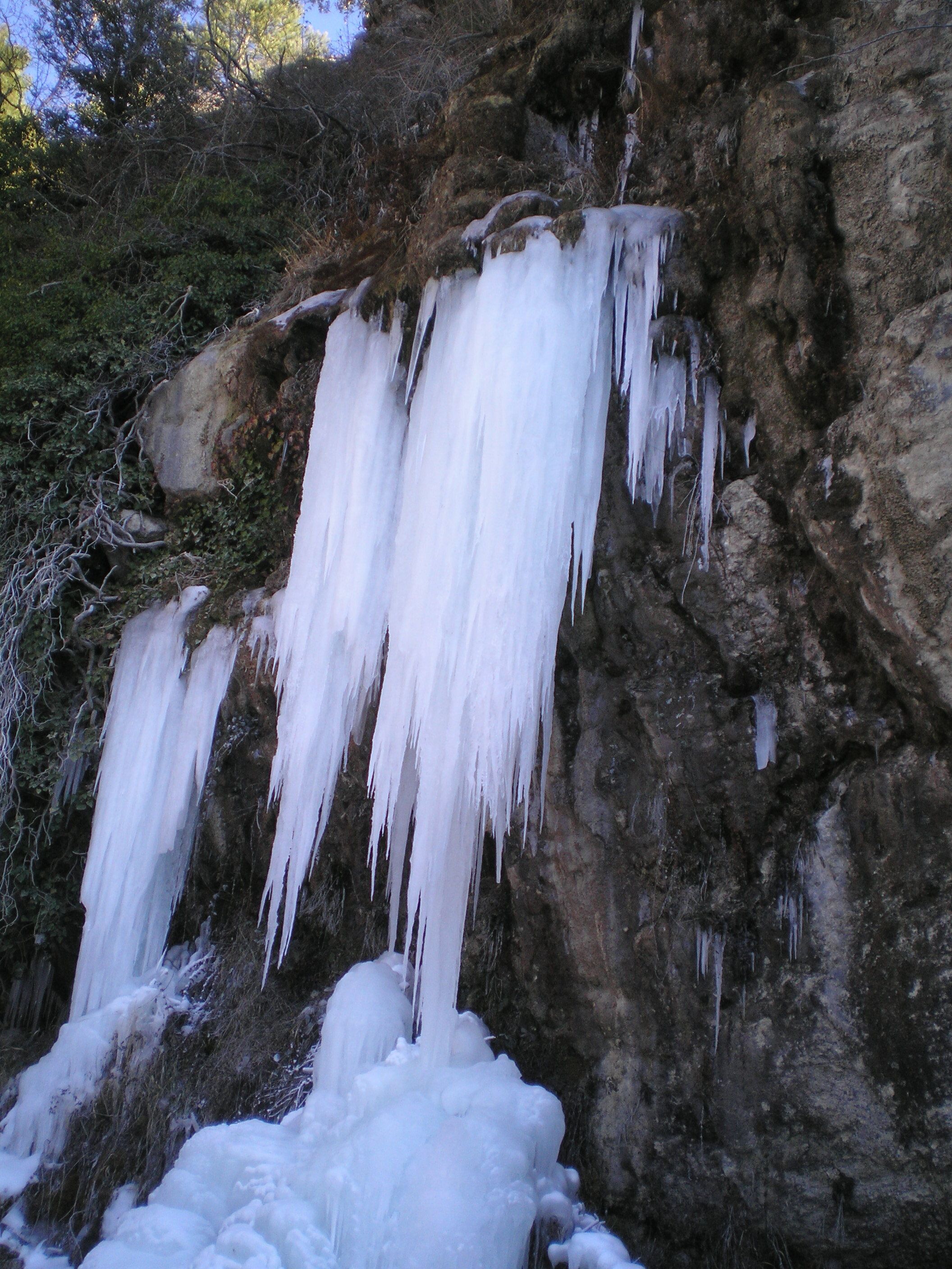 Picos de gelo pendurados em um penhasco rochoso.