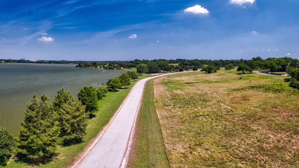 Uma estrada costeira com um lago, árvores e um céu limpo.