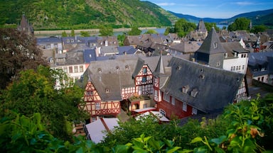 Uma cidade com casas tradicionais em enxaimel, um rio e colinas ao fundo.