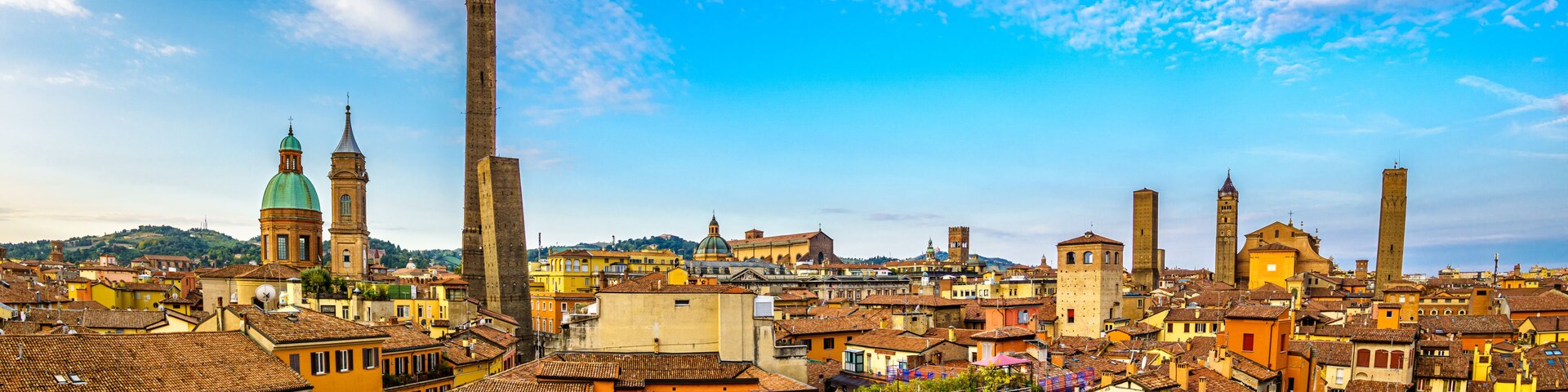 Paisagem urbana histórica com torres imponentes, edifícios com cúpulas e construções com telhados de terracota.