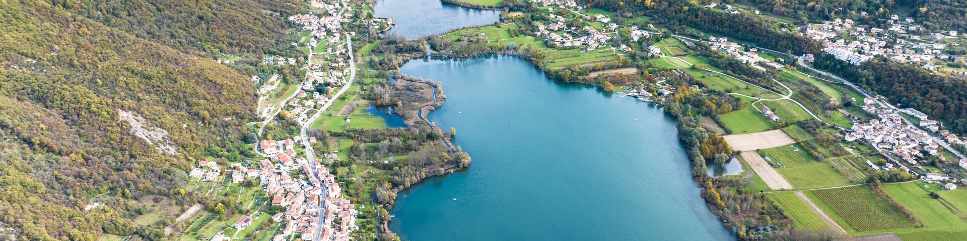 Vista aérea de uma cidade à beira de um lago, rodeada por colinas.