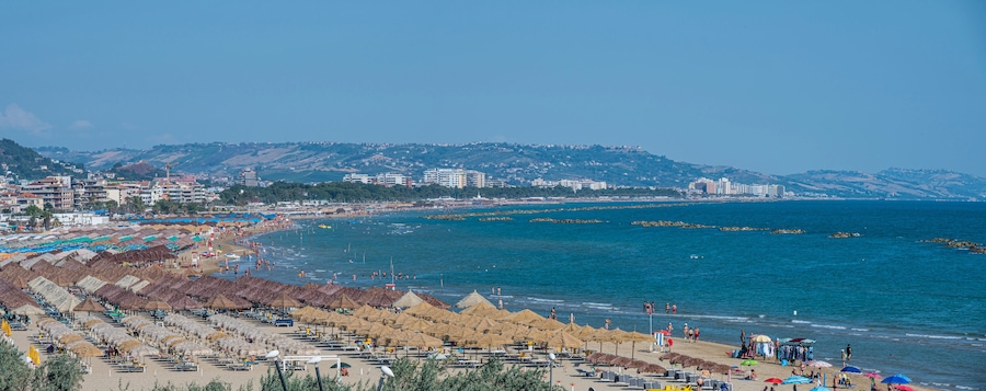 Uma cidade costeira com praia, guarda-sóis e edifícios.